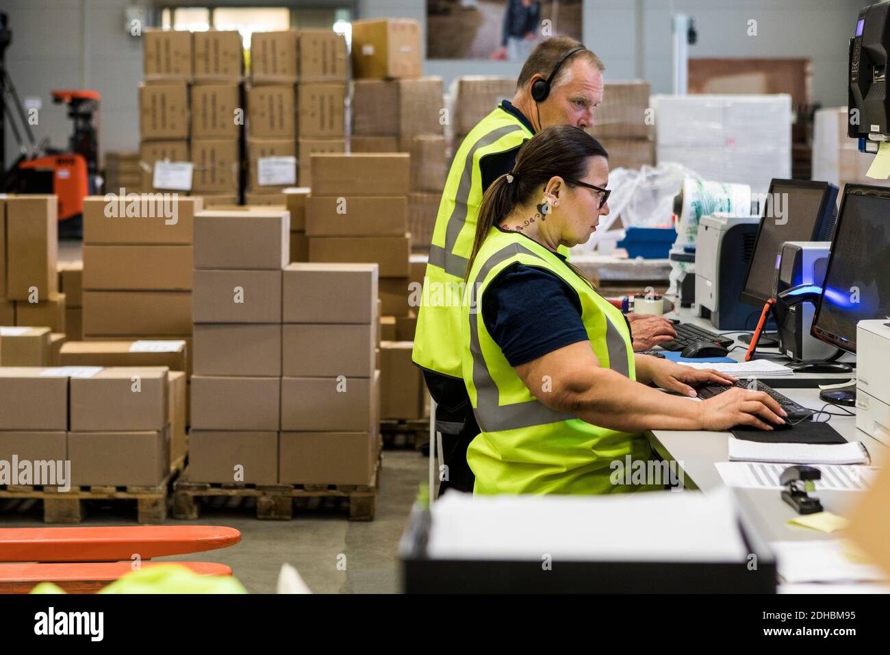 Side view of confident workers using computers at desk in distribution ...