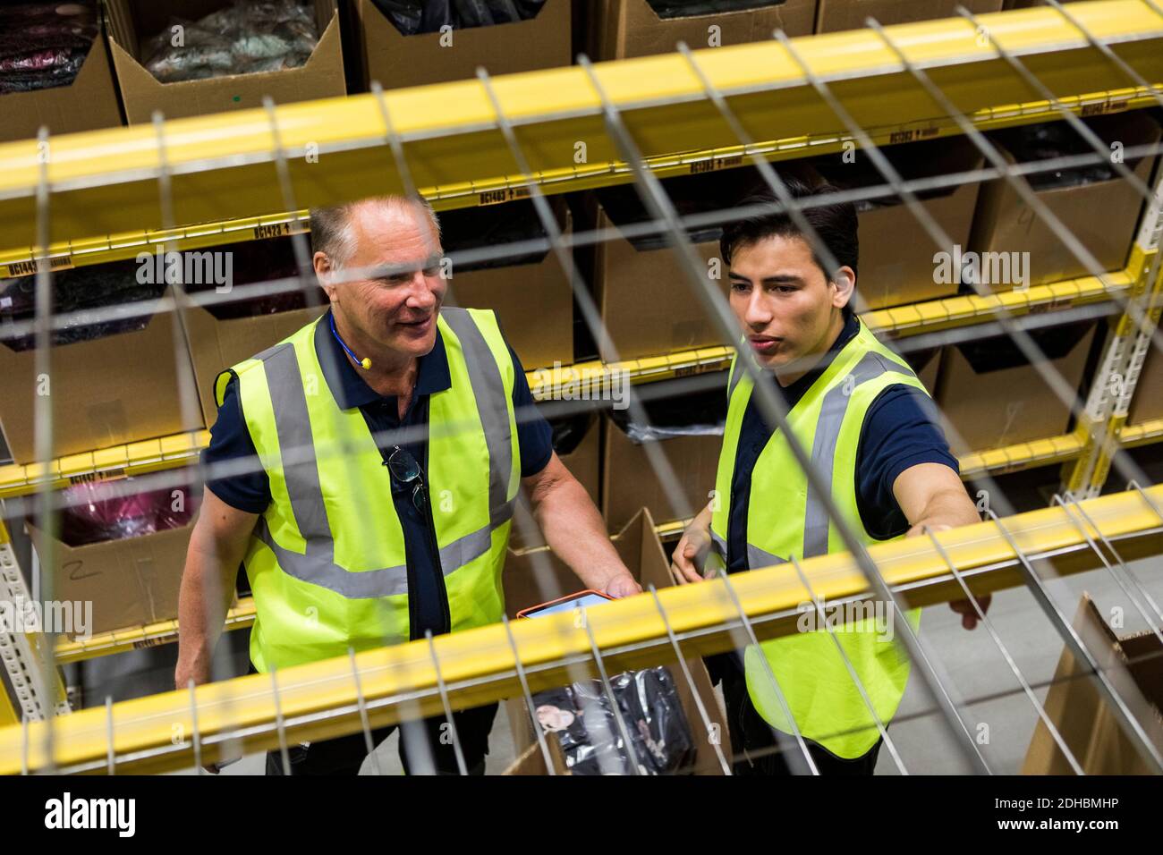 High angle view of male coworkers discussing while seen through rack ...