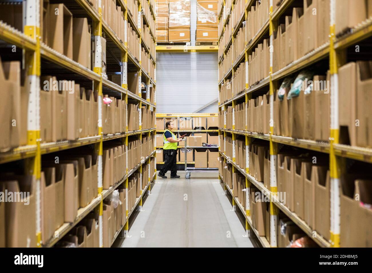Full length side view of mature female warehouse worker pushing cart ...