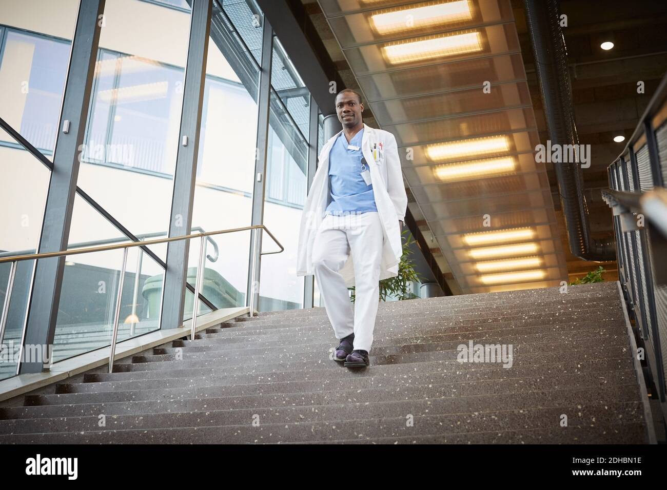 Low angle view of confident male doctor moving down on staircase at ...
