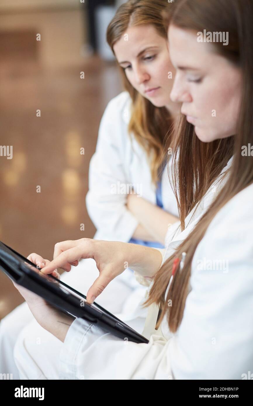 Confident female doctors discussing over digital tablet in corridor at ...