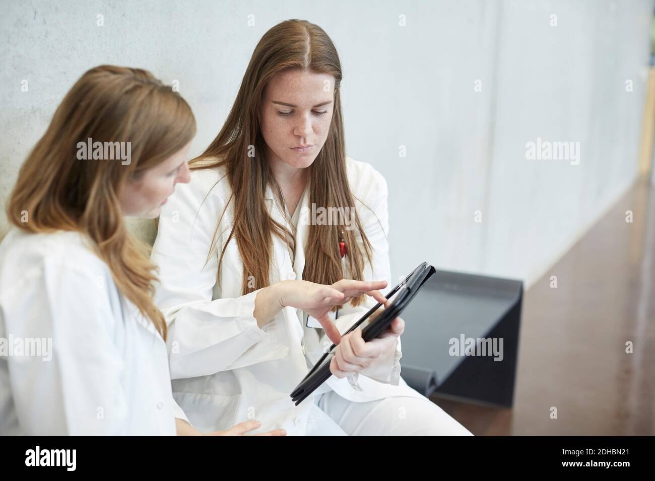 Confident female doctors discussing over digital tablet while sitting ...