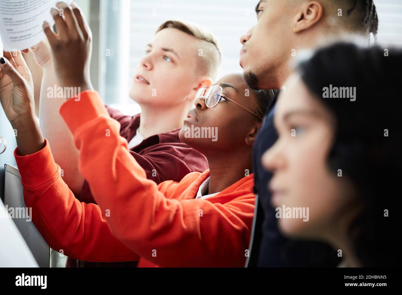 Male and female university students checking test results on bulletin ...