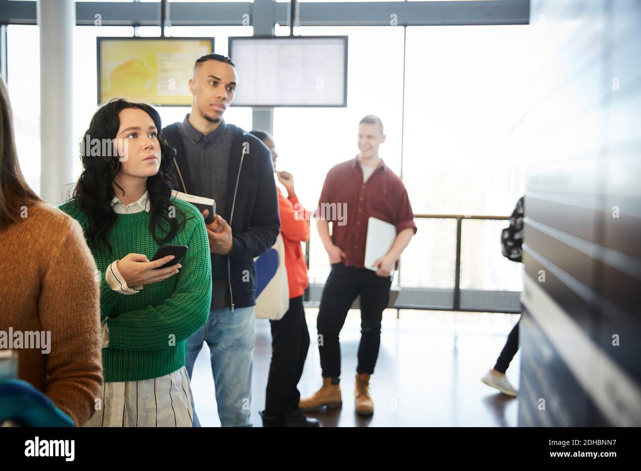 Male and female young bored students waiting in line at university ...