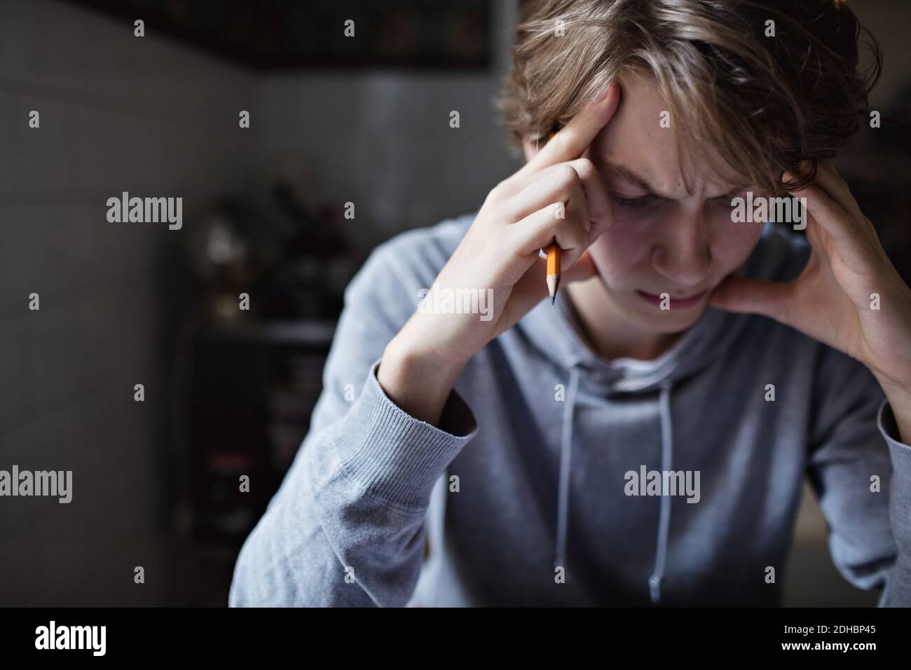 Stressed teenage boy with head in hands studying at home Stock Photo ...