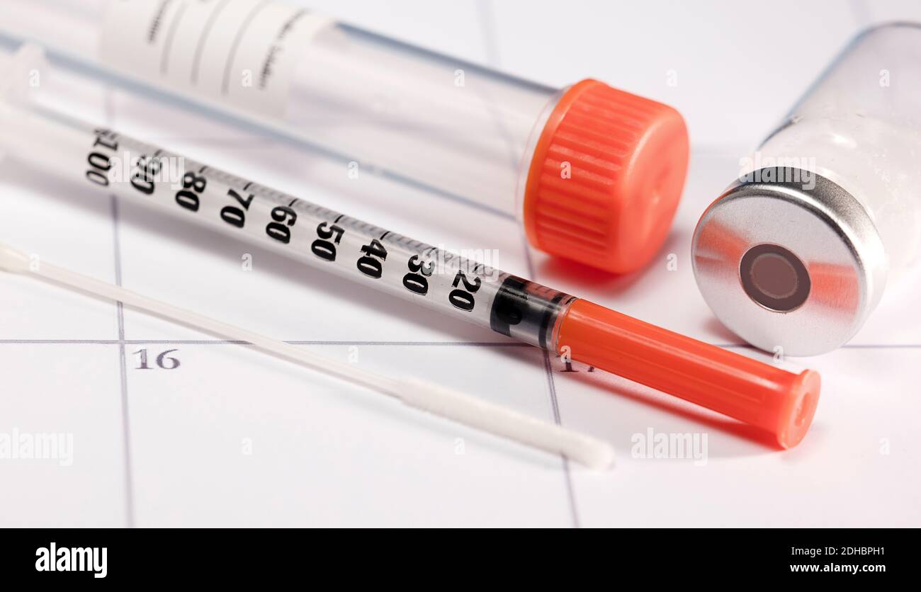 syringe with orange cannula and transparent vial with aluminum closure ...