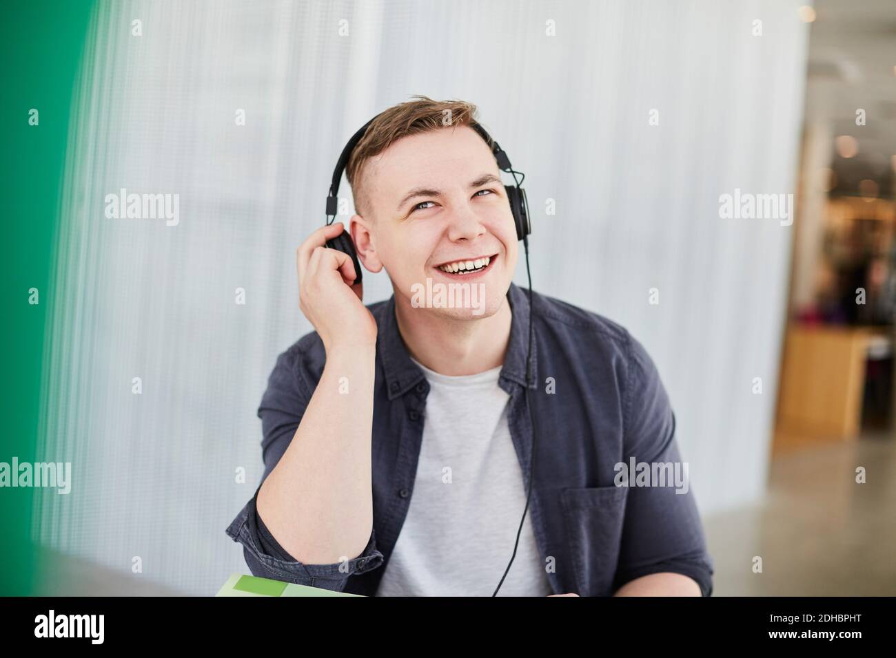 Smiling male student with headphones studying in university cafeteria ...