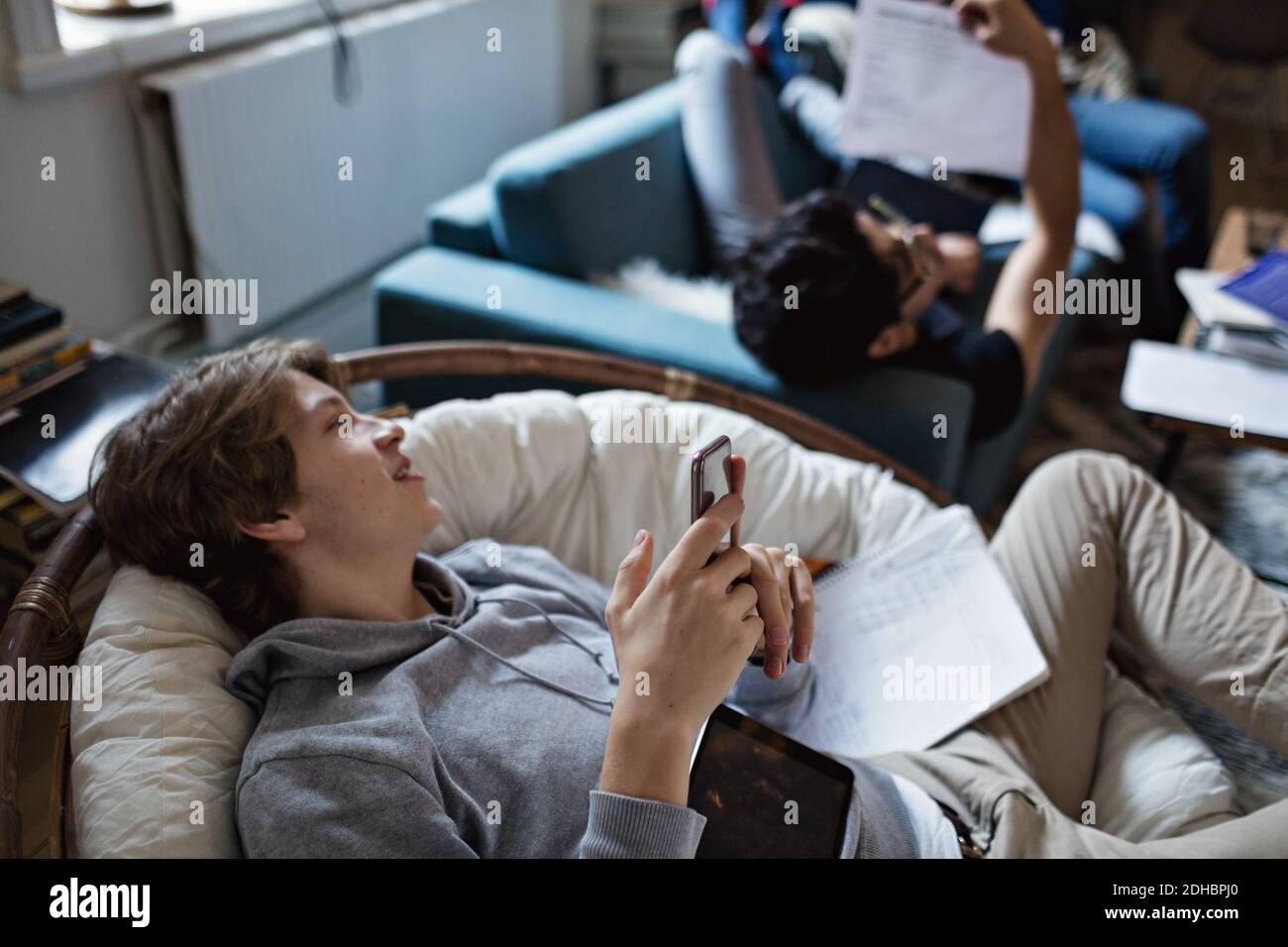 Distracted teenage boy using social media on mobile phone while ...