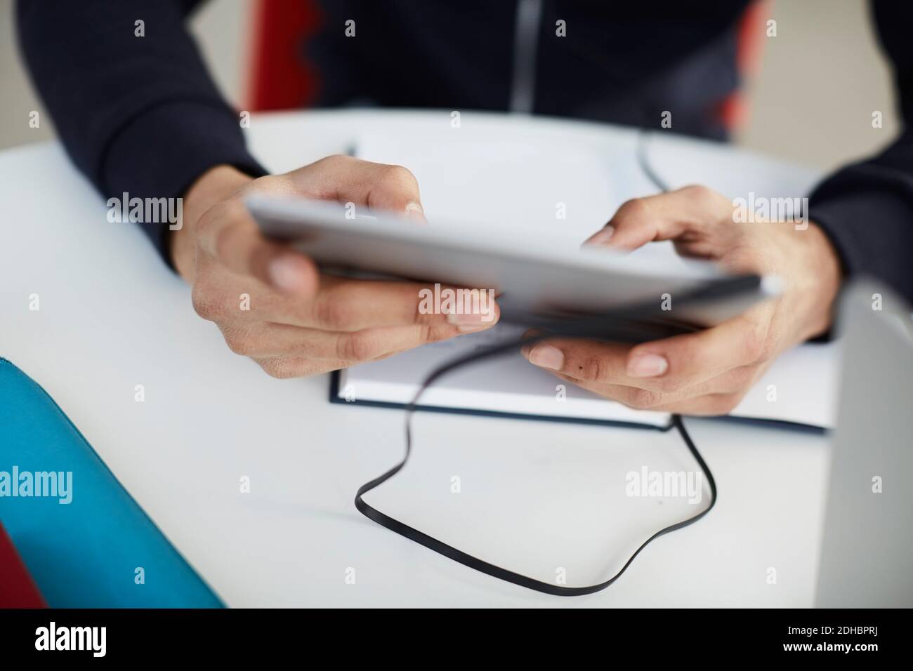 Midsection of university student using digital tablet at table while ...