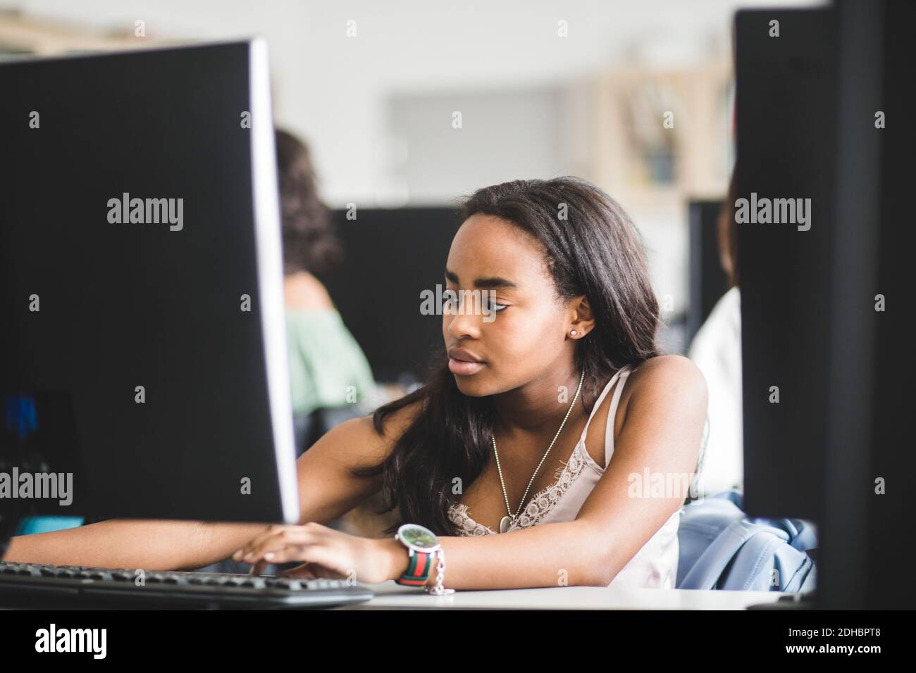 Confident girl using computer at desk in classroom Stock Photo - Alamy