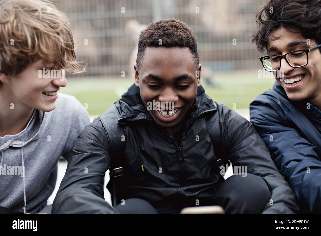 Cheerful male friends using social media after sports practice during ...