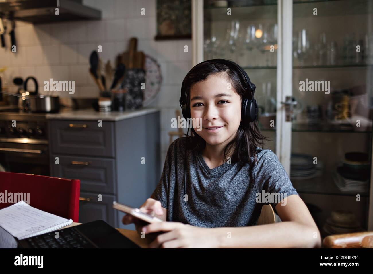 Portrait of smiling boy using mobile phone for E-learning at home Stock ...