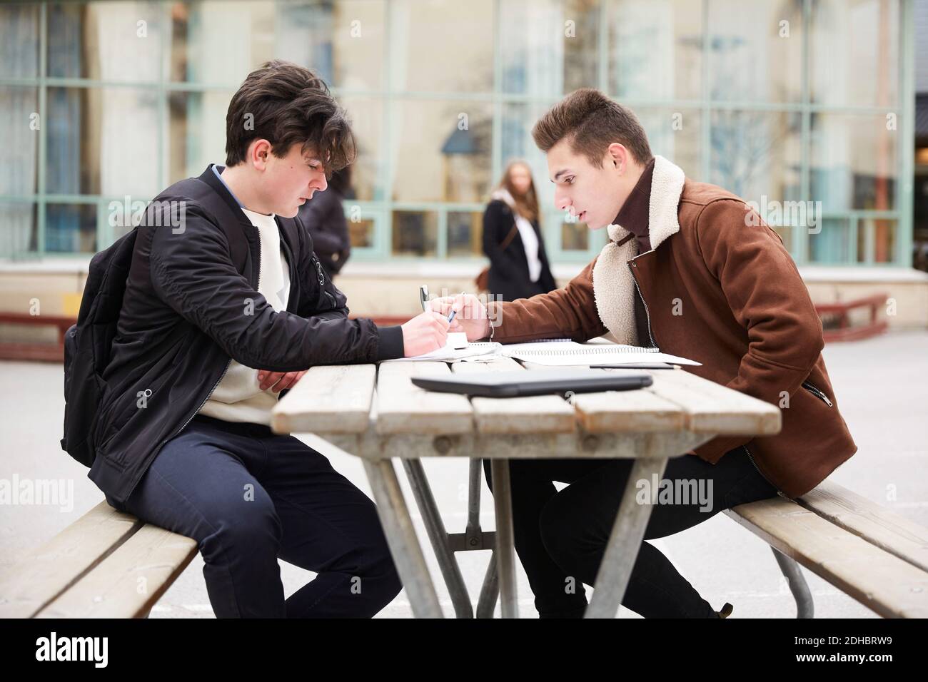 Male teenage friends studying at table in schoolyard Stock Photo - Alamy