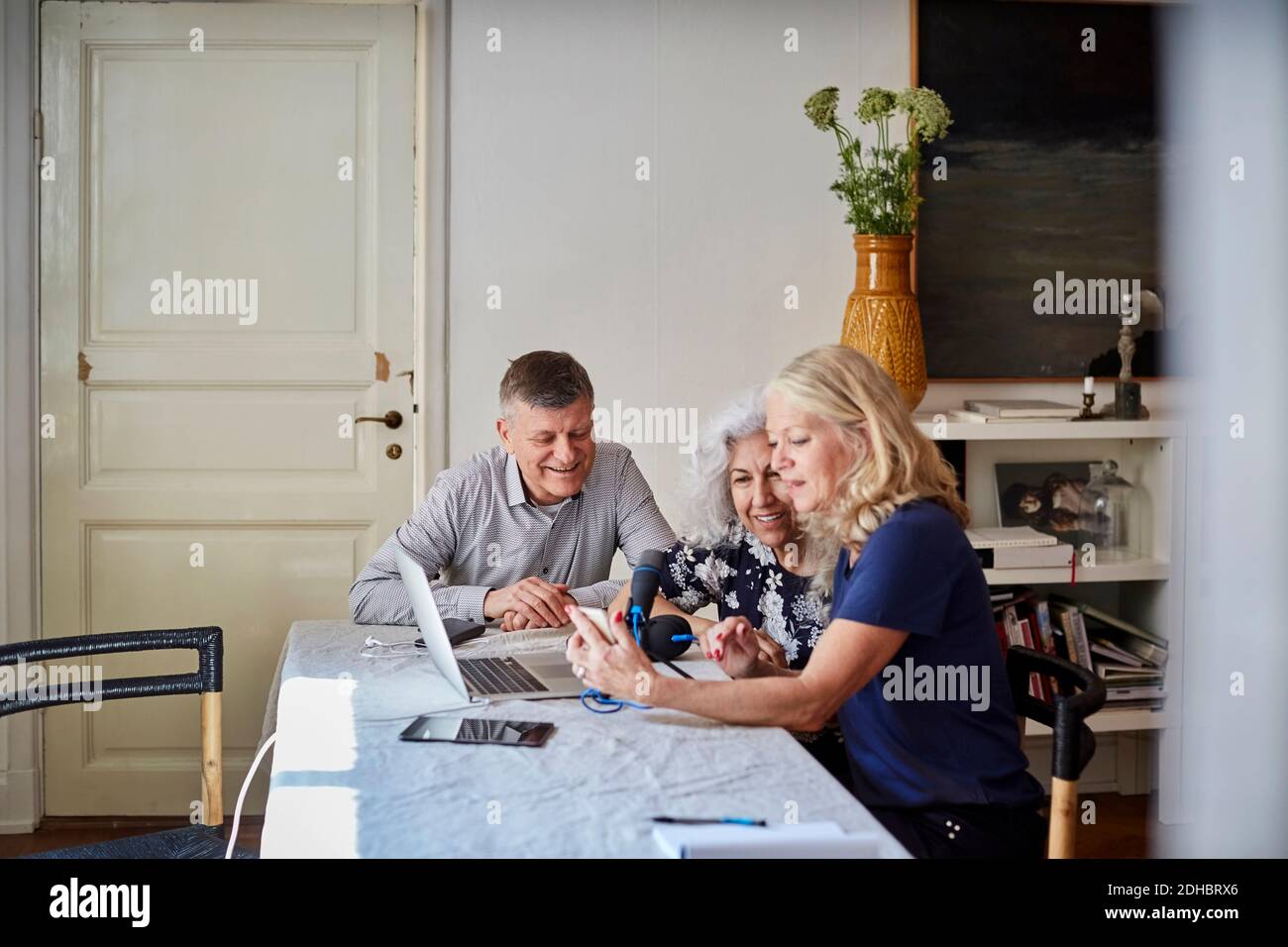 Happy senior male and females vlogging at table in living room Stock ...
