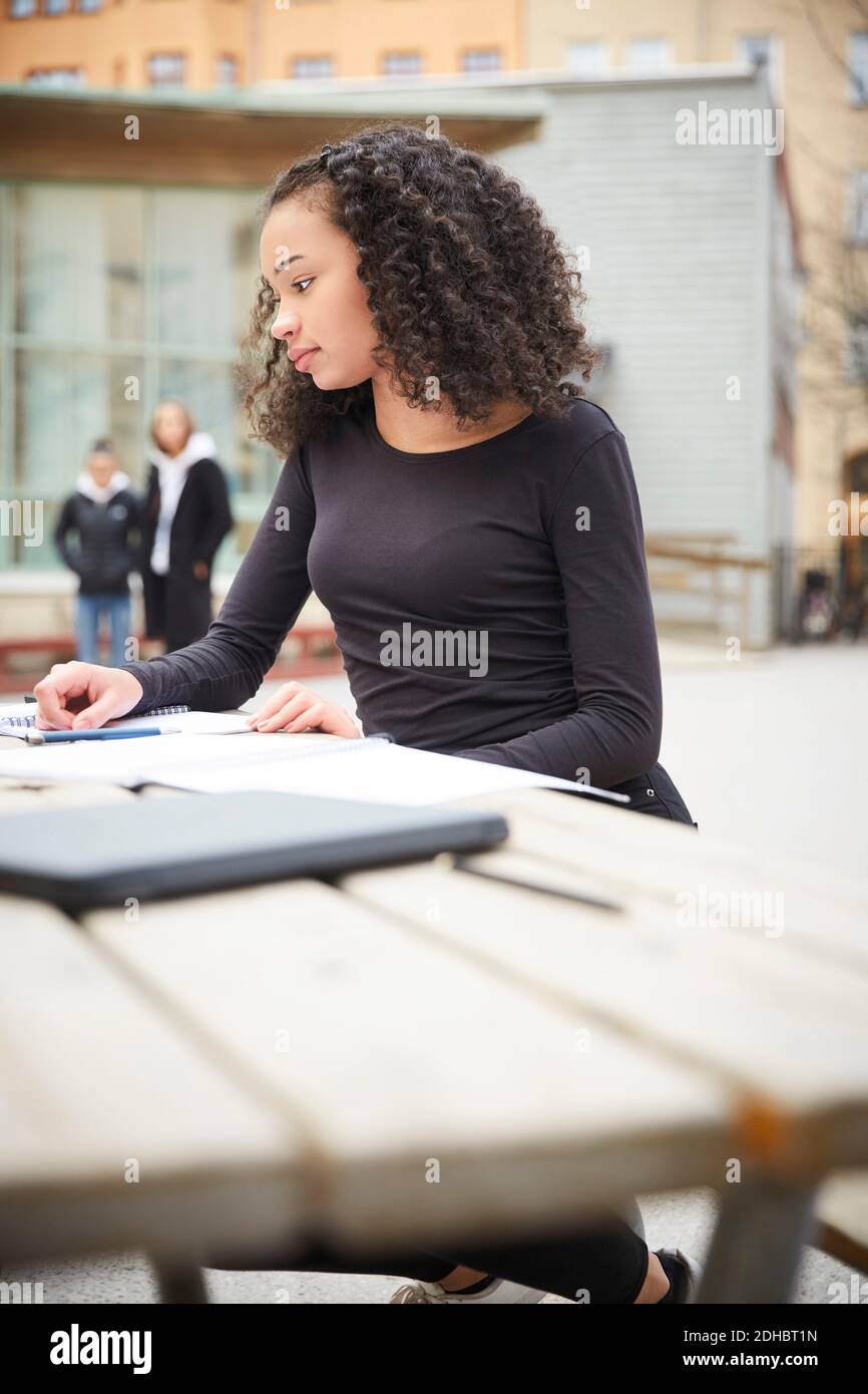 Teenage girl sitting at table in schoolyard Stock Photo - Alamy