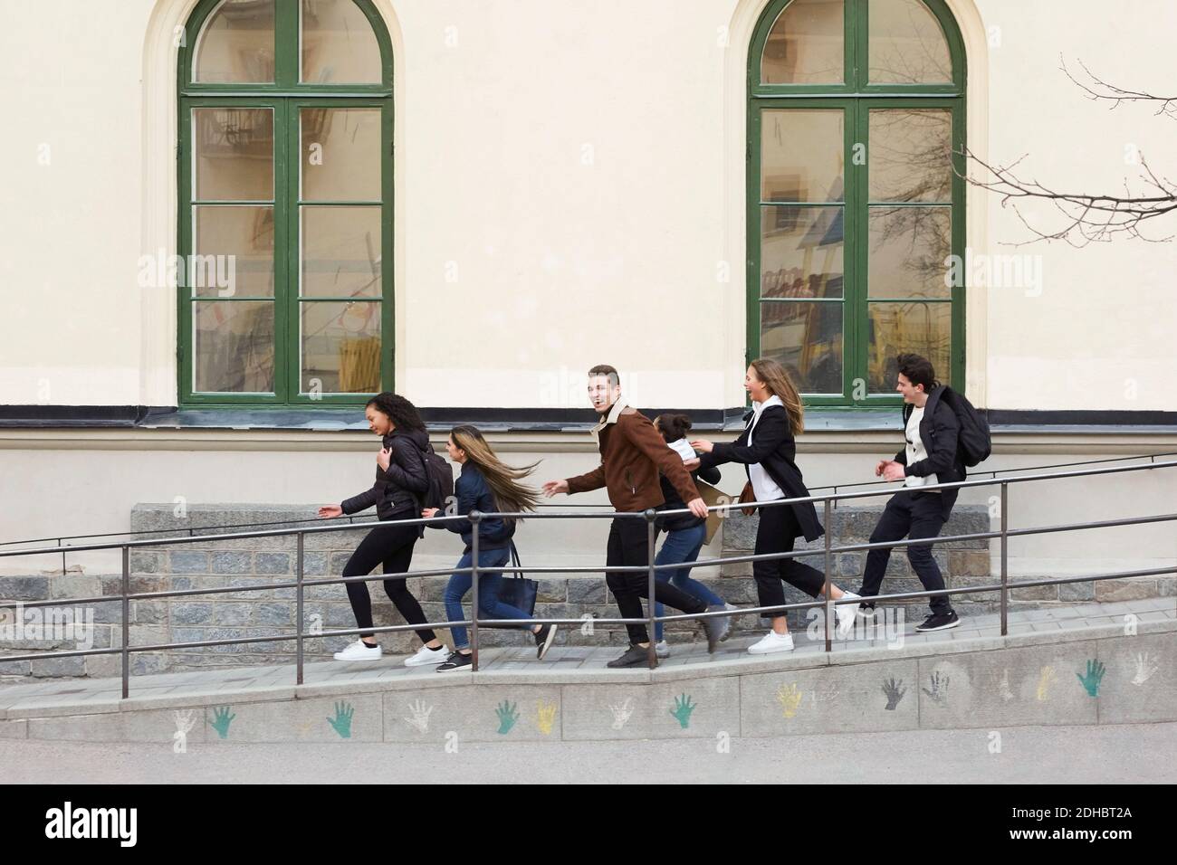 Cheerful teenage girls and boys running on walkway of high school Stock ...