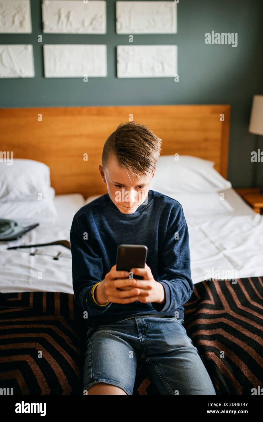 Boy in hotel room checking his mobile Stock Photo - Alamy