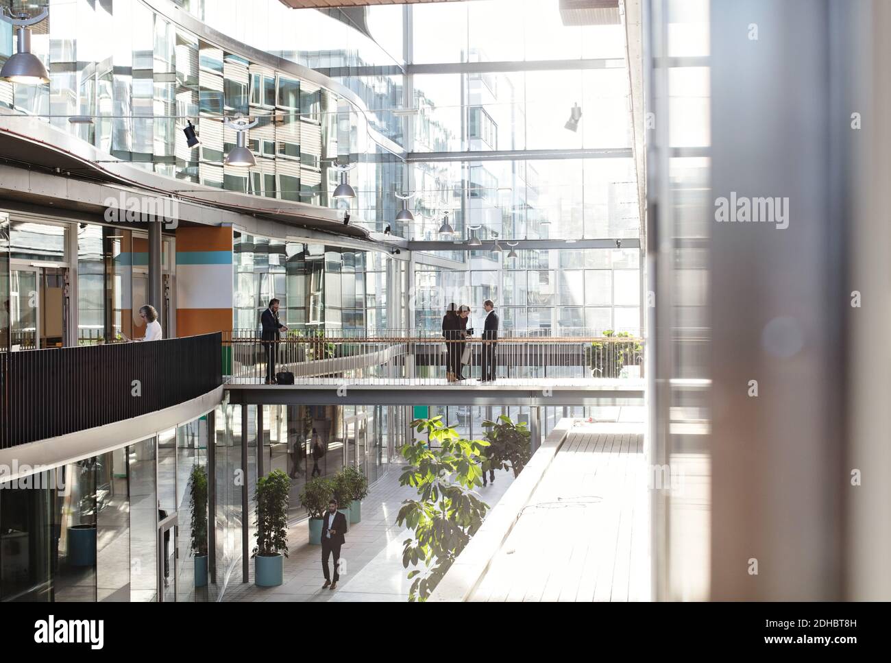Male and female business people standing at modern office atrium Stock ...