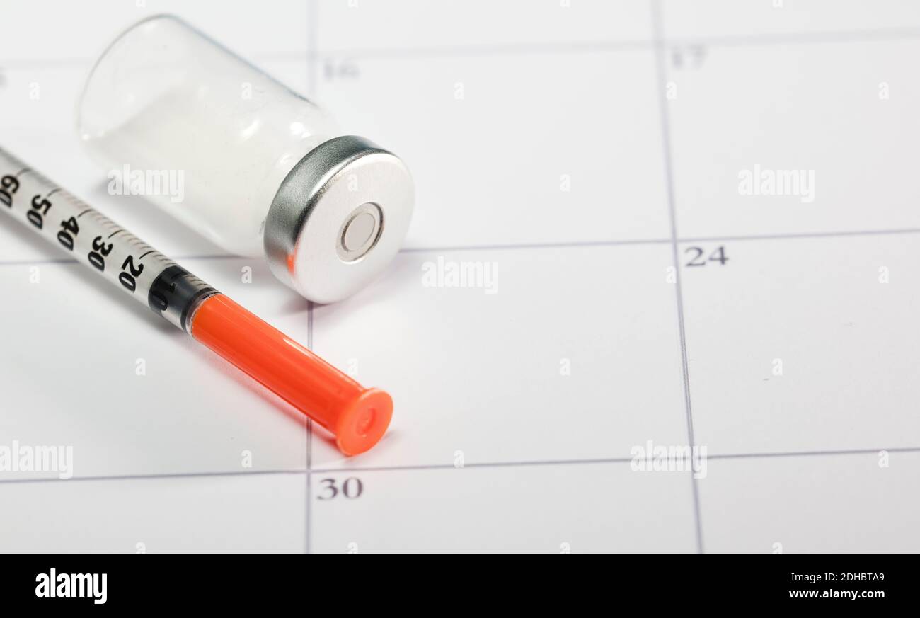 syringe with orange cannula and transparent vaccine vial with aluminum ...