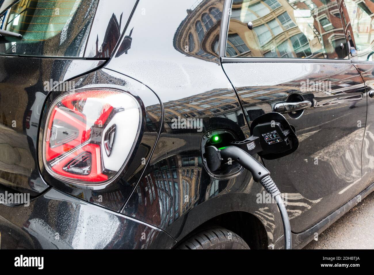 Electric car plugged in for charging close up with green led indicator ...