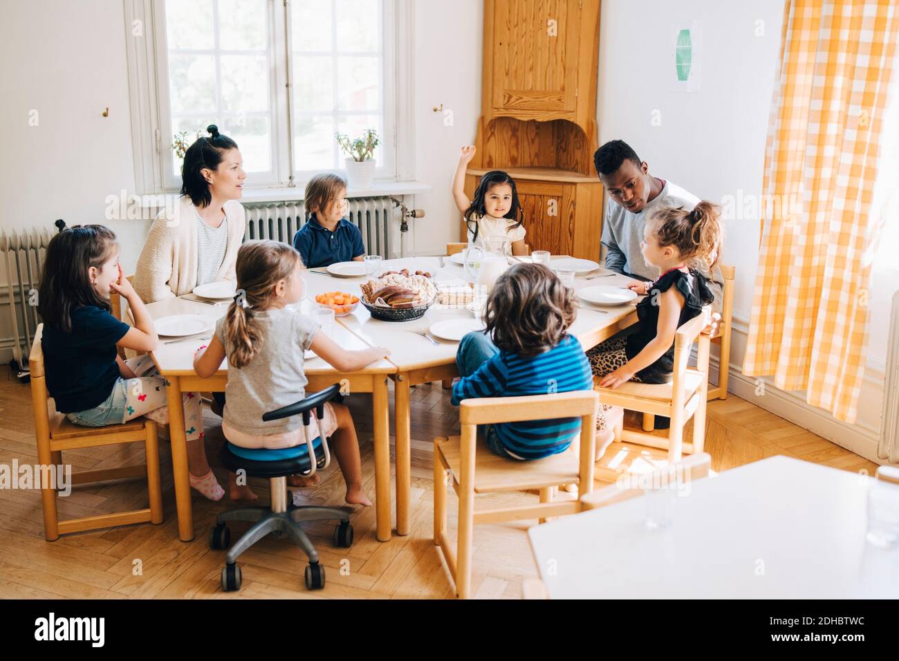 Teachers and students sitting at table during lunch break in classroom ...