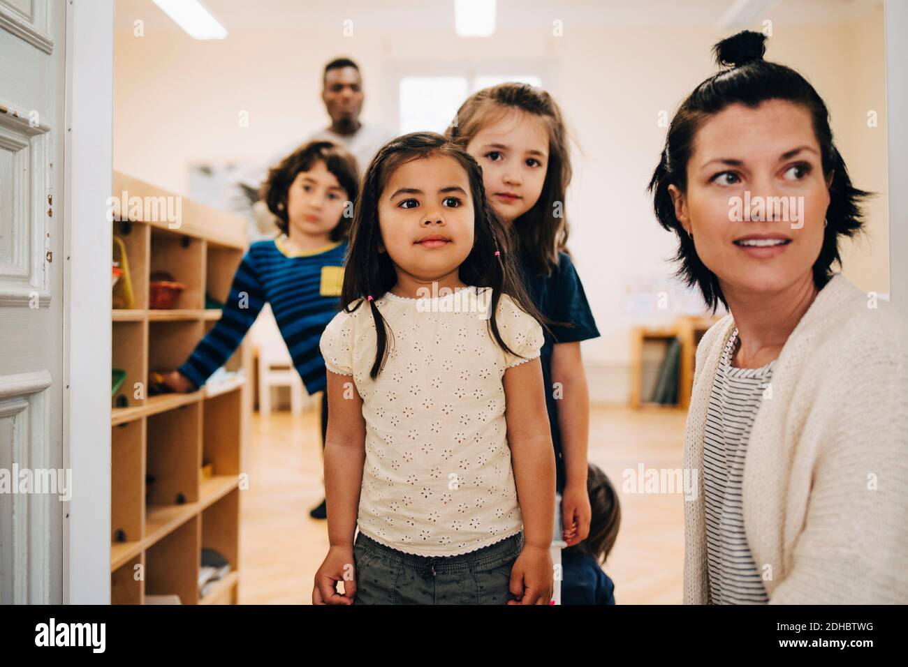 Teacher and students looking away in classroom at child care Stock ...