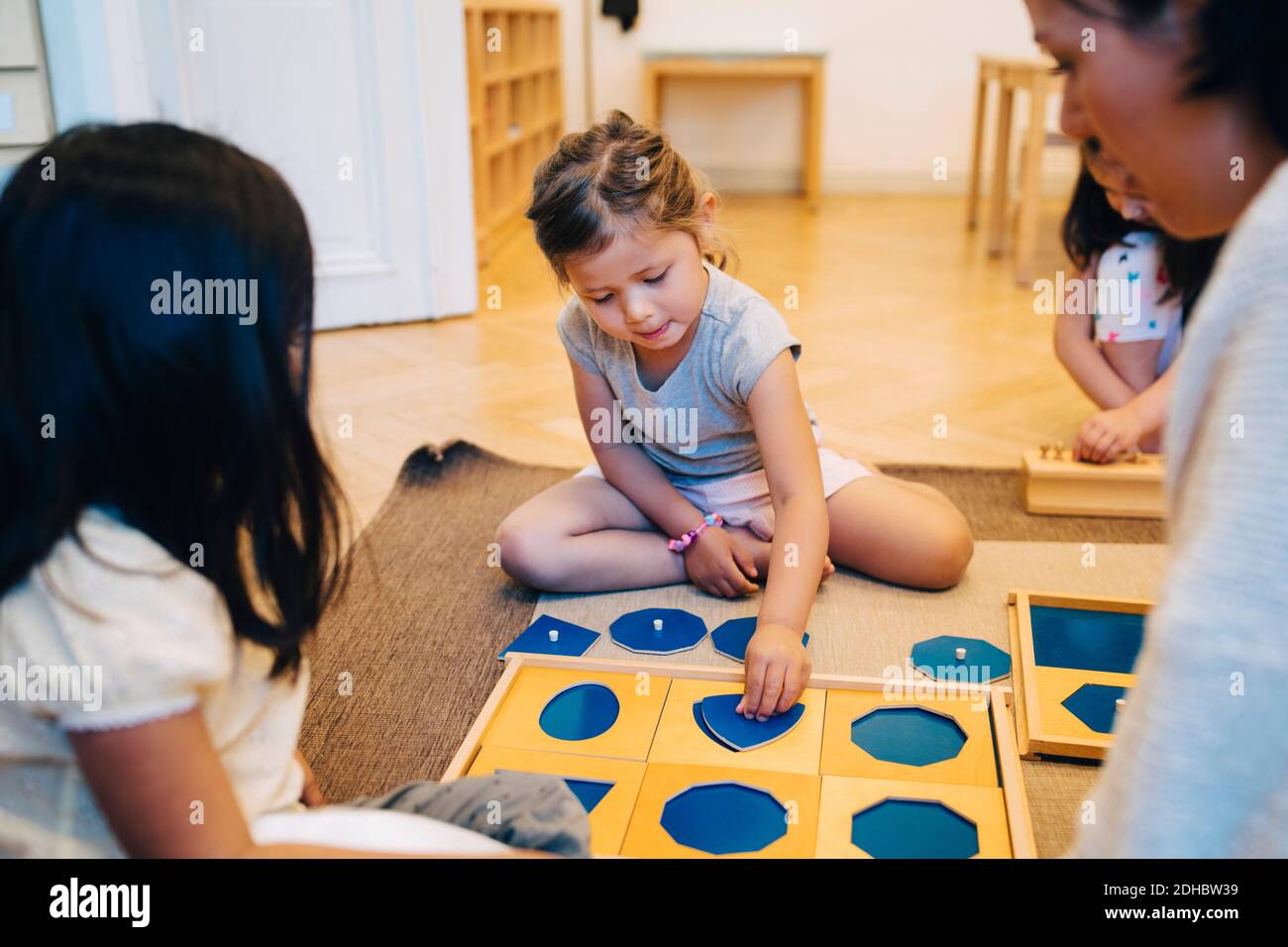 Teacher and student looking at girl playing puzzle game in classroom ...