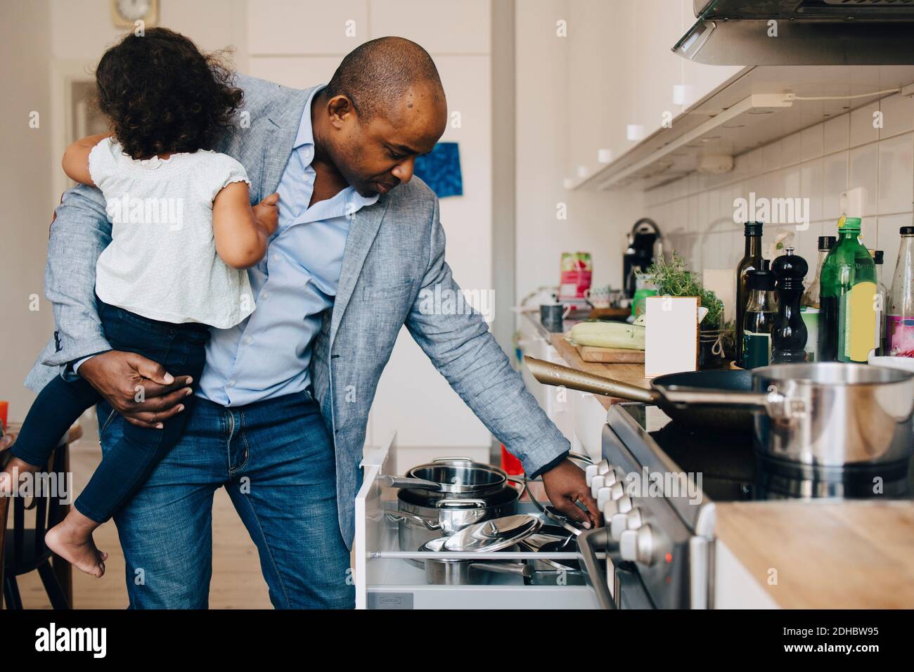 Father carrying daughter while looking at utensils in kitchen Stock ...