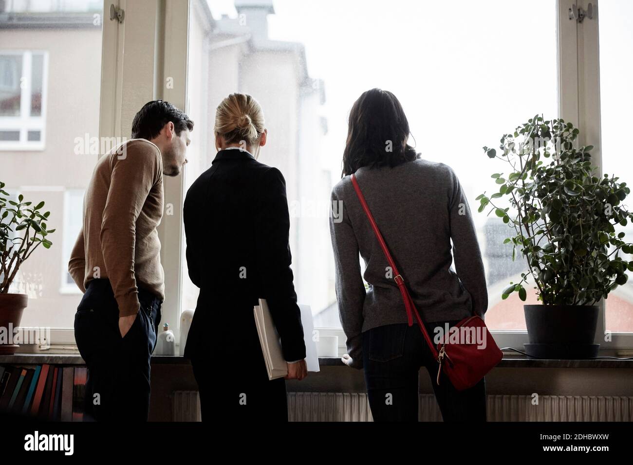 Real estate agent and customers looking through window of new house ...