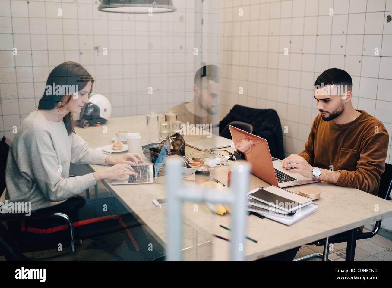 Young male and female computer programmers using laptops for encryption ...