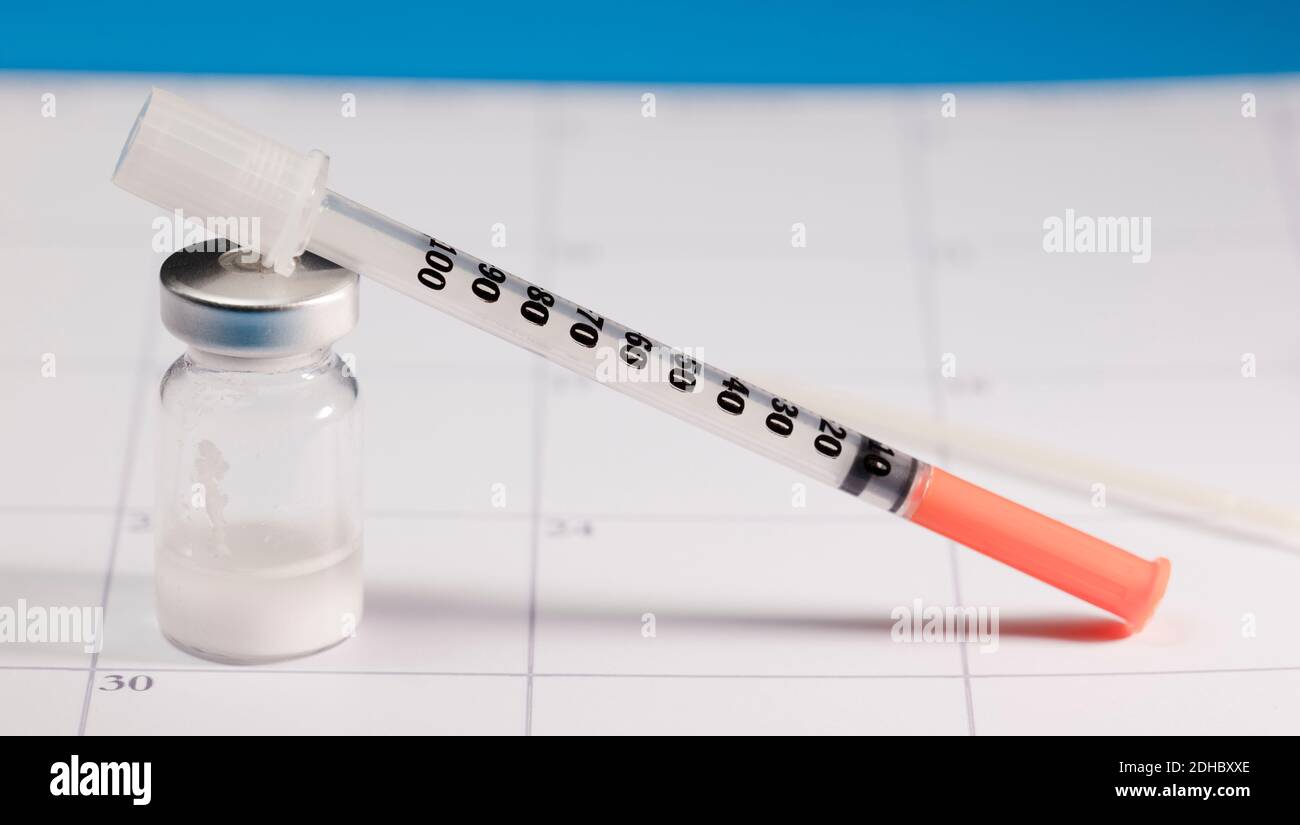 syringe with orange cannula and transparent vaccine vial with aluminum ...