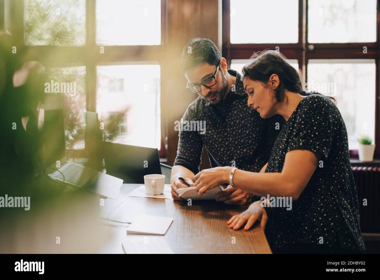 Multi-ethnic business people discussing over documents at desk in ...