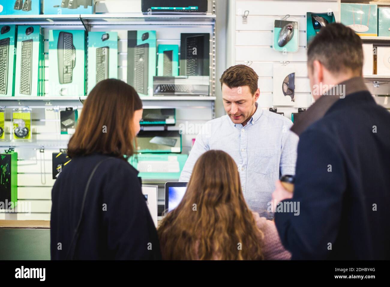 Salesman showing computer equipment to customers in electronics store ...