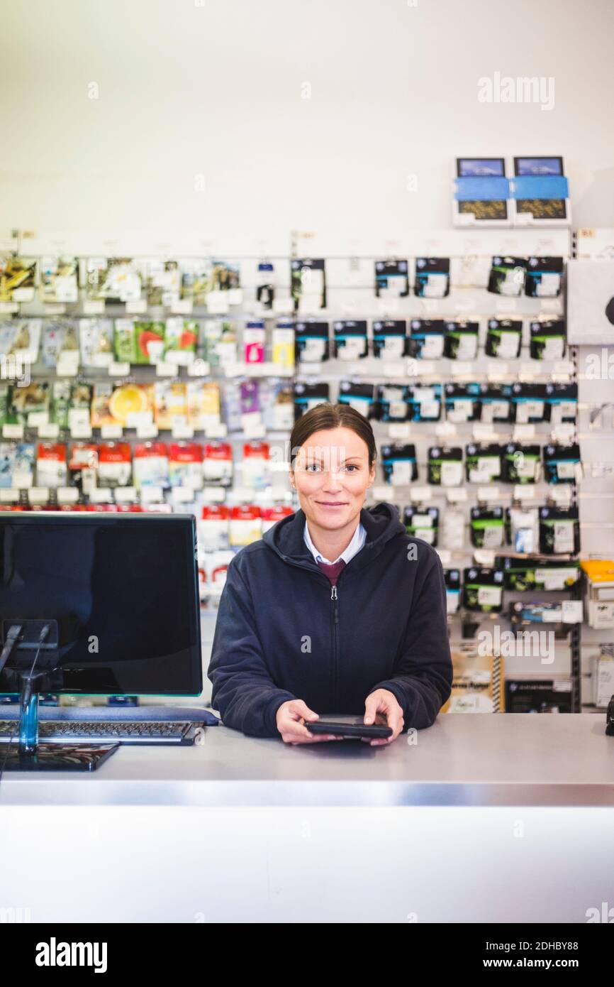 Portrait of a confident mature store clerk with arms crossed in ...