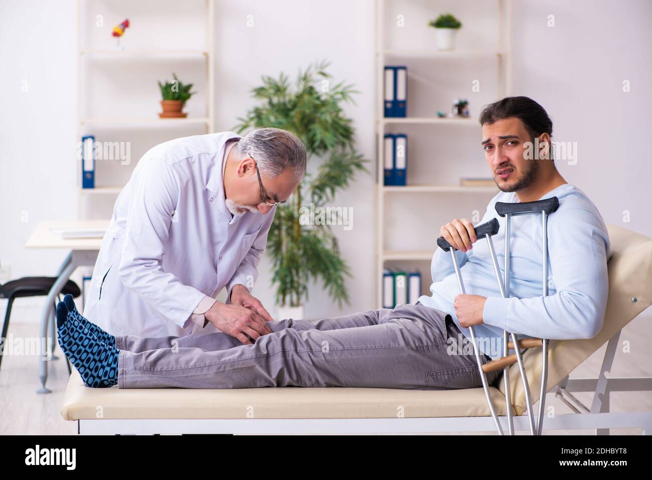 Young leg injured man visiting old doctor osteopath Stock Photo - Alamy