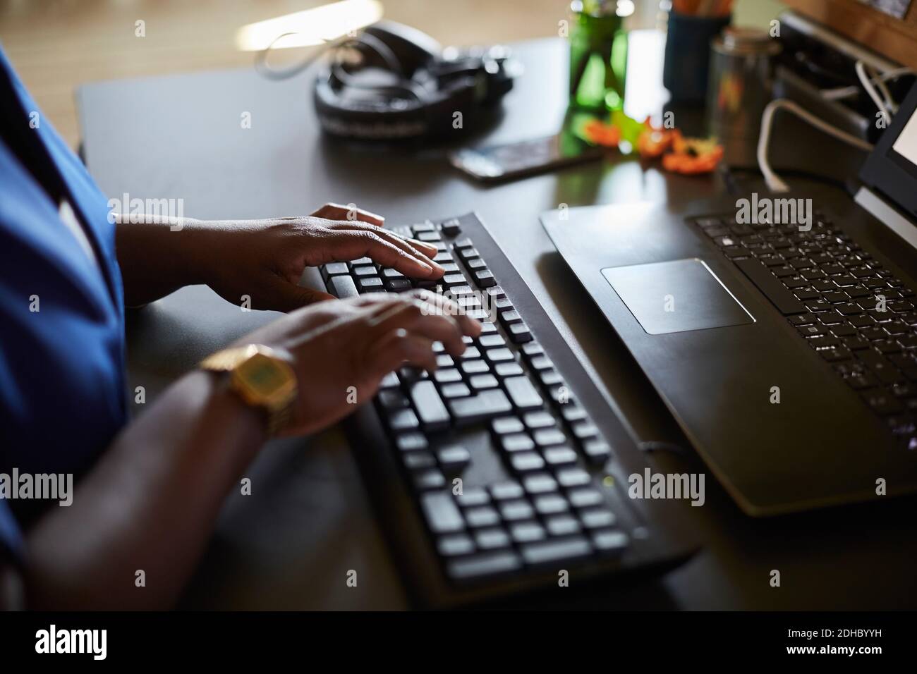 Midsection of businesswoman typing on keyboard at desk in creative ...