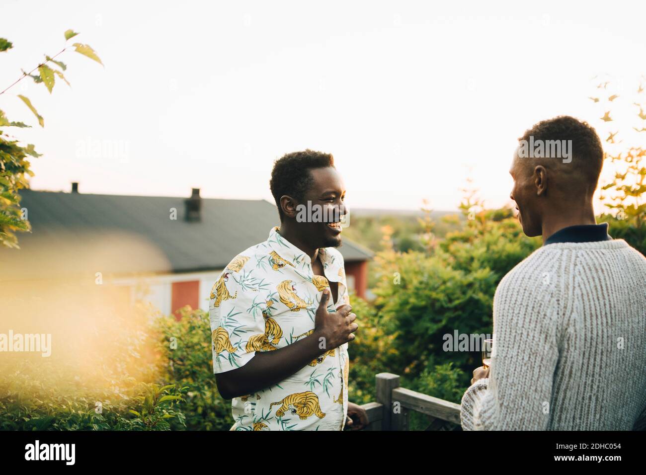 Happy friends talking while standing in balcony during sunset Stock ...
