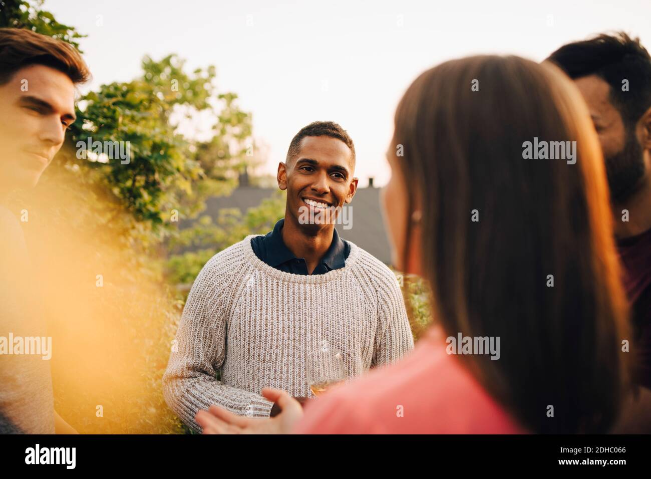Multi-ethnic friends talking while standing in yard during social ...