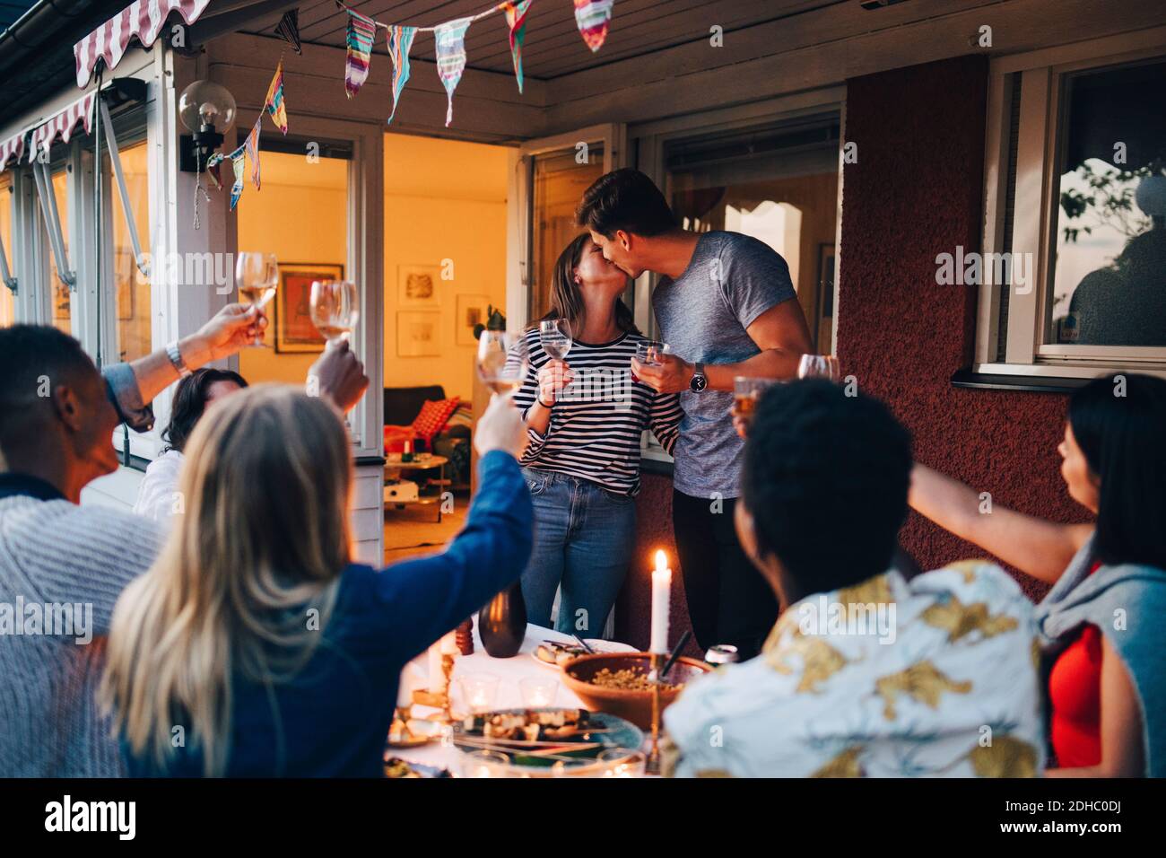 Man and woman kissing during dinner party with friends Stock Photo - Alamy