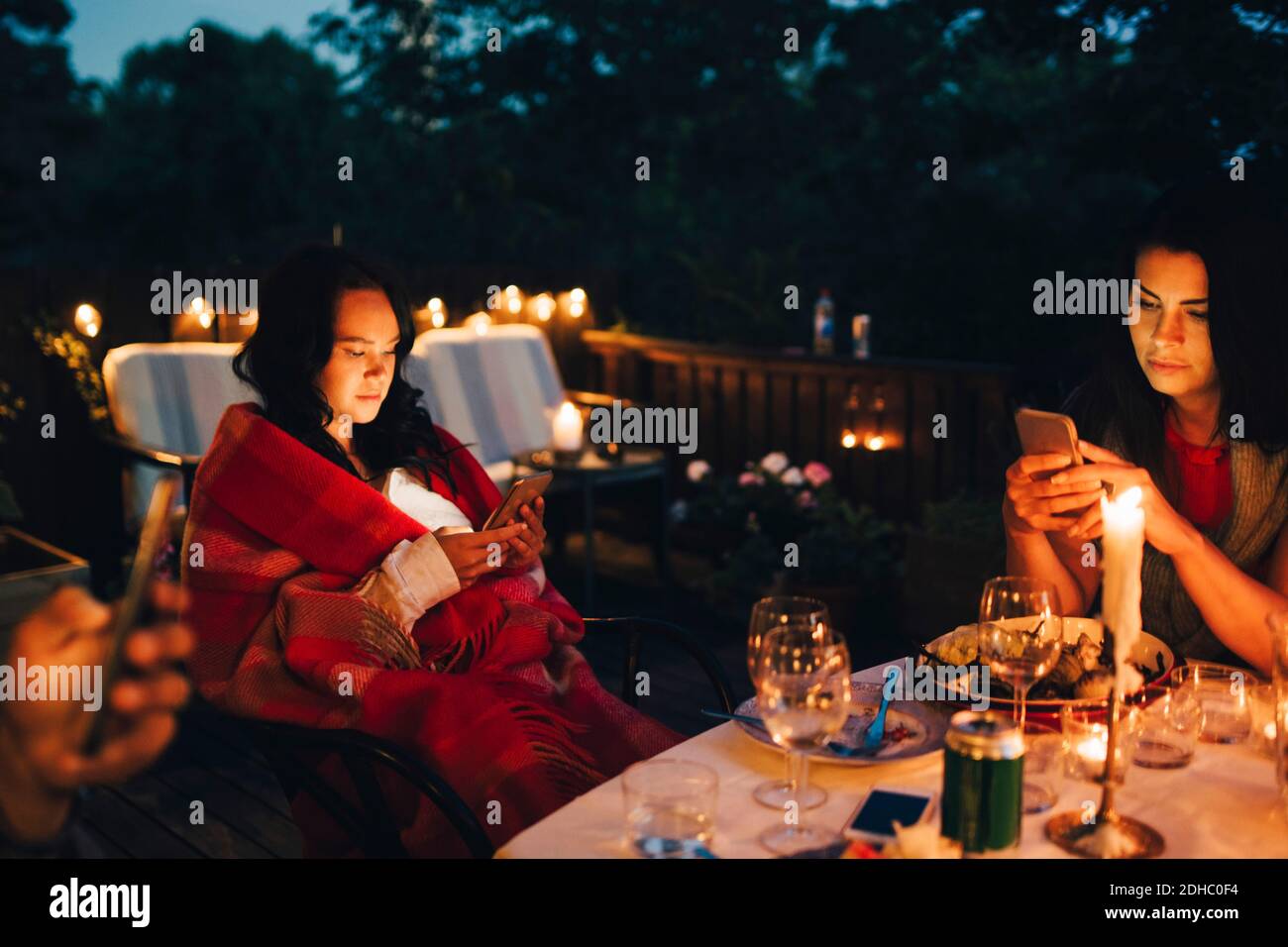 Female friends using mobile phones at table during dining party Stock ...