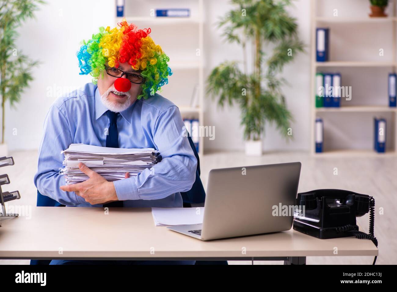Old businessman clown working in the office Stock Photo - Alamy