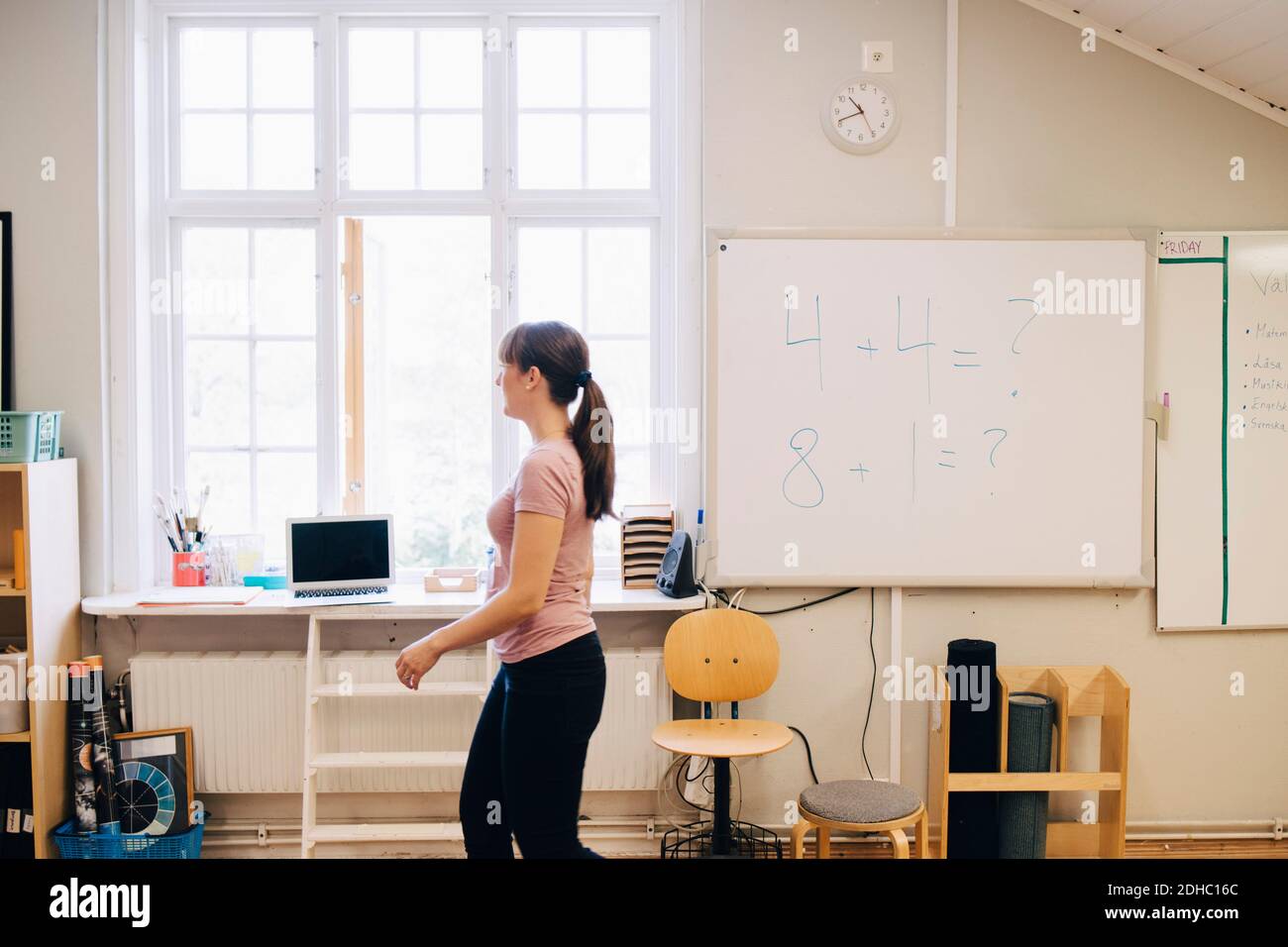 Side view of teacher walking by whiteboard with mathematics in ...