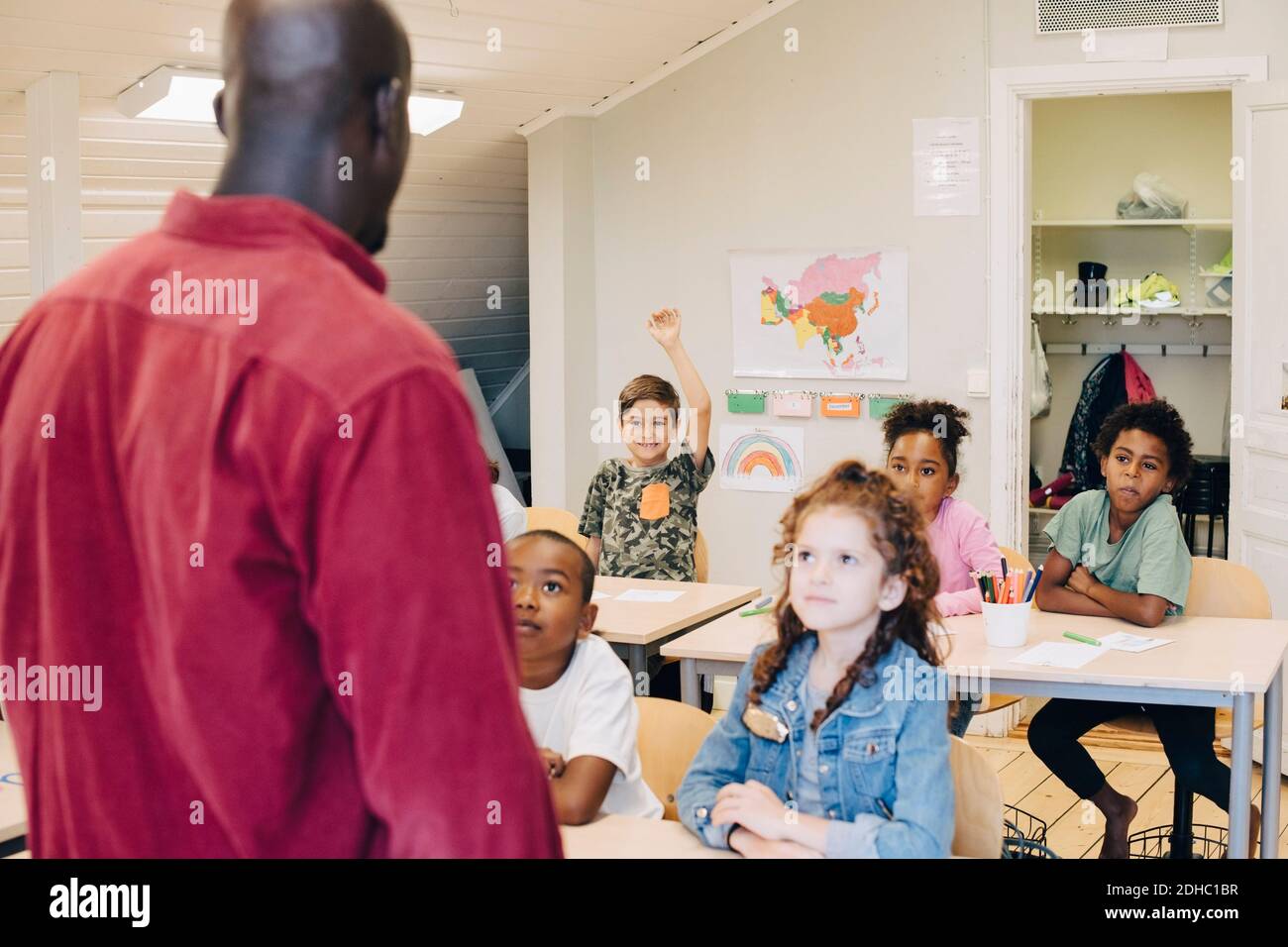 Rear view of male teacher teaching students in classroom Stock Photo ...