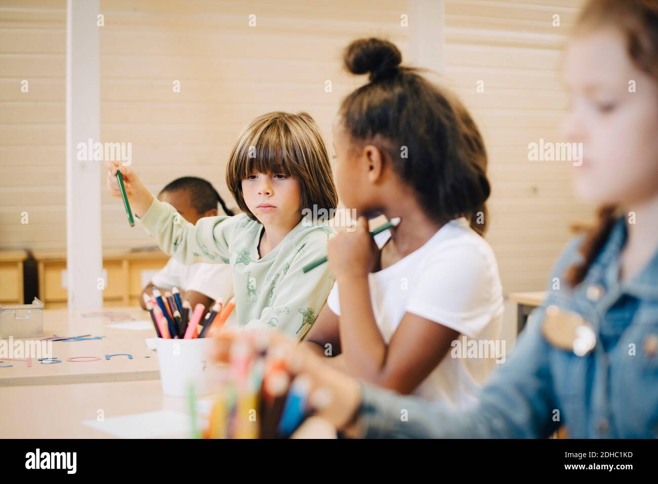 School friends drawing on paper at desk in classroom Stock Photo - Alamy