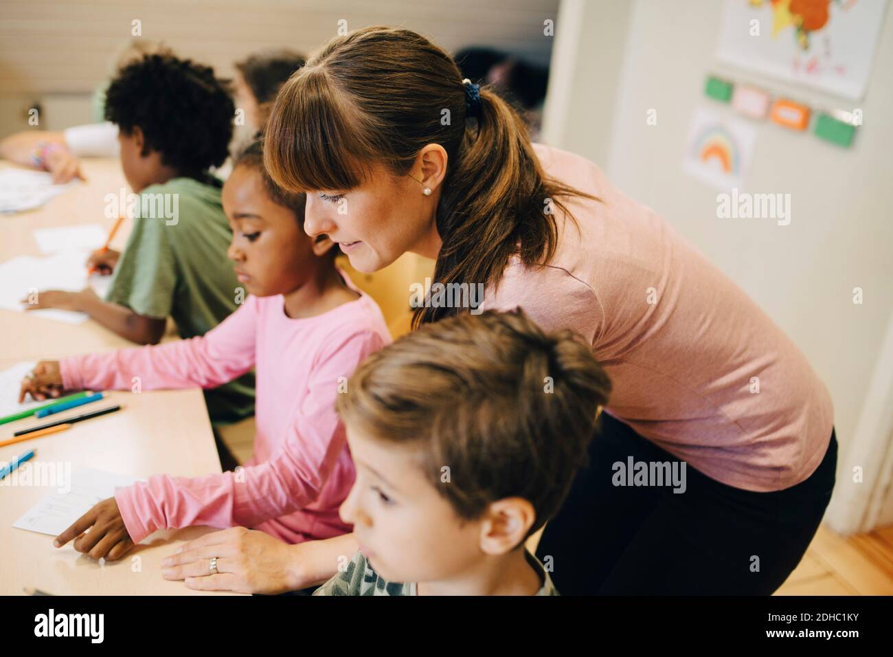 High angle view of teacher guiding students at desk in classroom Stock ...