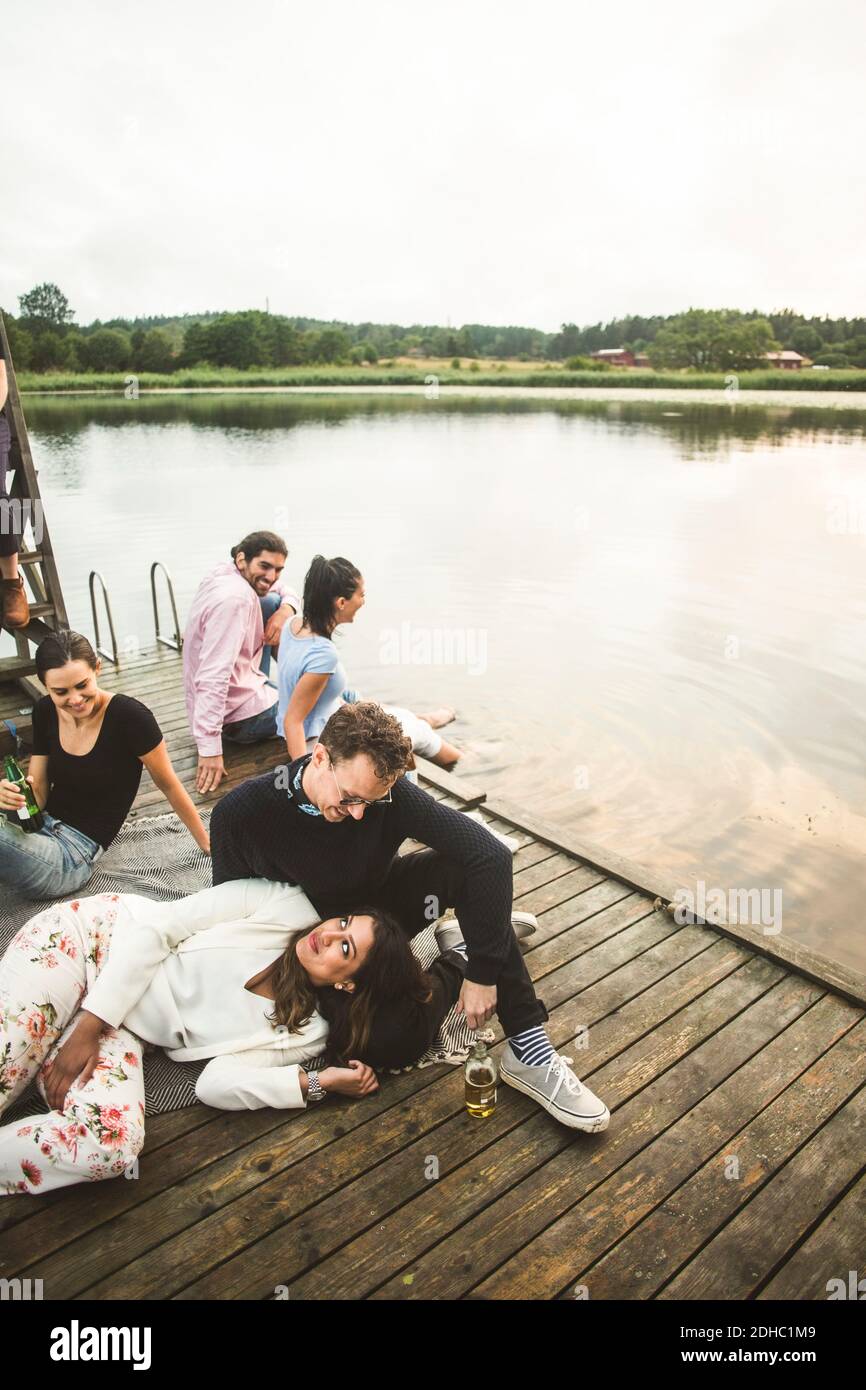 Couple with friends on jetty over lake during weekend getaway Stock ...
