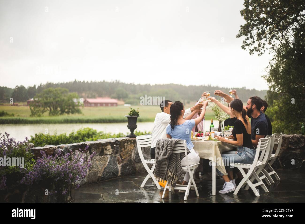 Male and female friends toasting drinks at dining table while spending ...