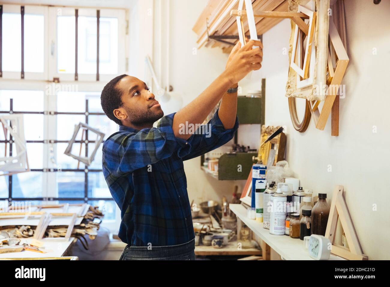 Confident young male craftsperson holding frame at workshop Stock Photo ...