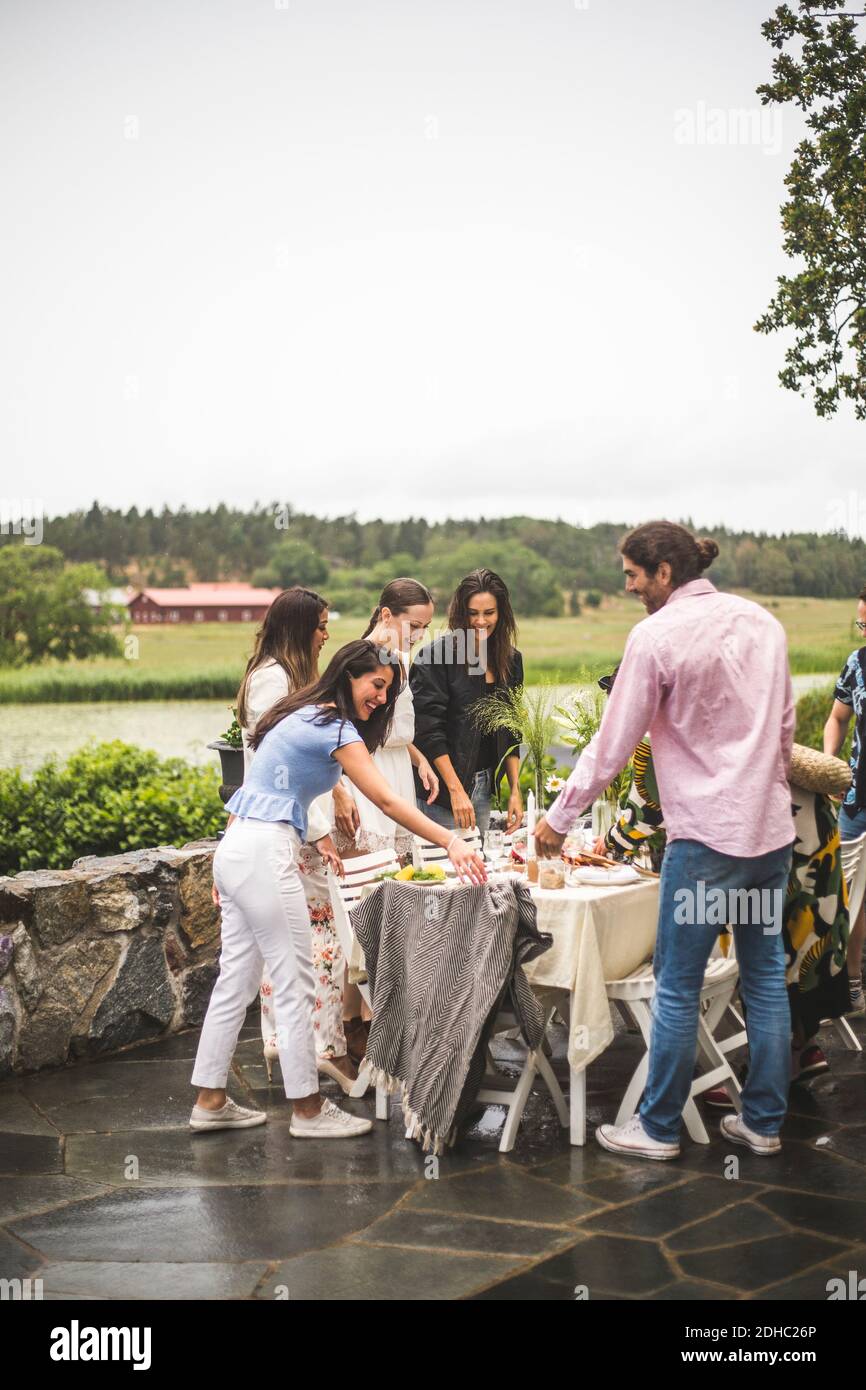 Multi-ethnic friends smiling while standing around dining table in ...