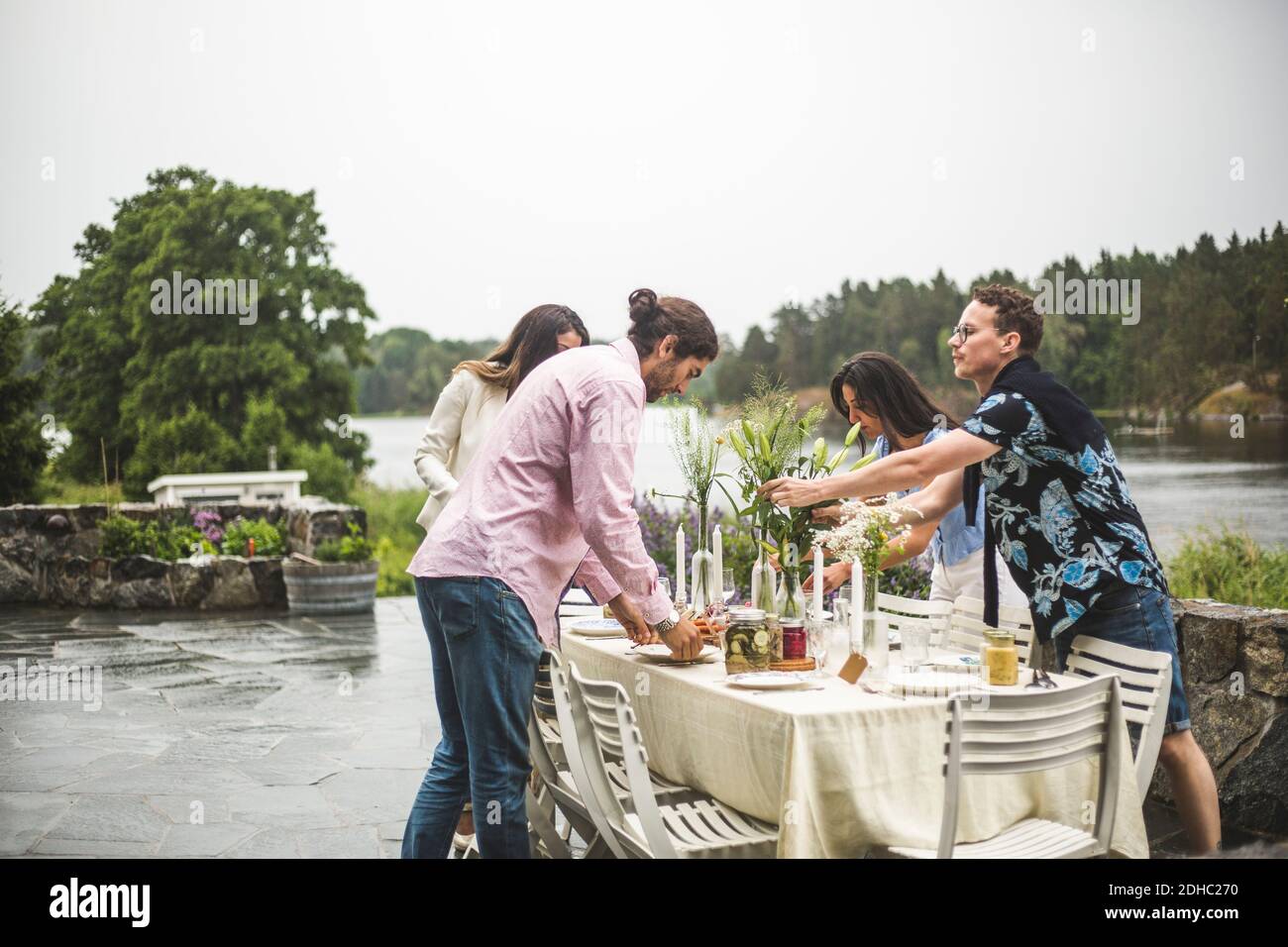 Multi-ethnic friends setting table for dinner party in backyard against ...